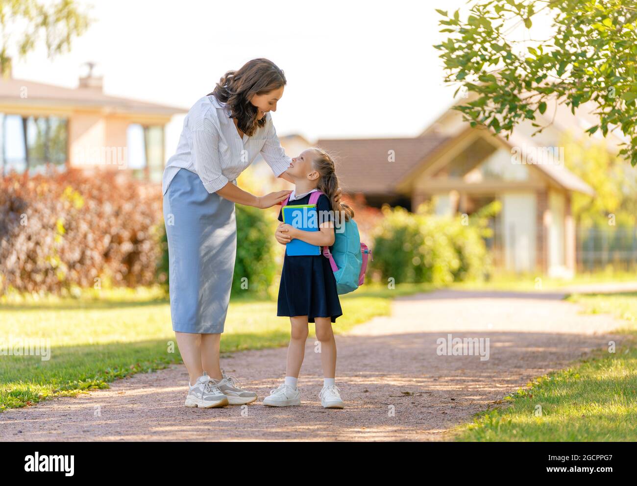 Parent and pupil of primary school going hand in hand. Woman and girl ...