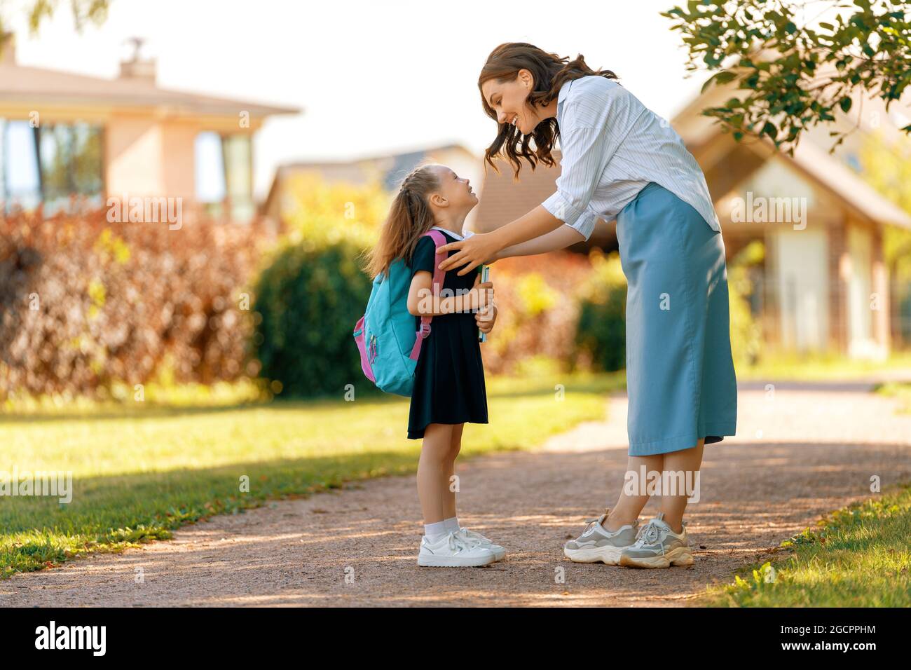 Parent and pupil of primary school going hand in hand. Woman and girl ...
