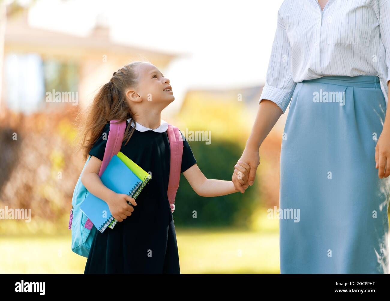 Parent and pupil of primary school going hand in hand. Woman and girl ...