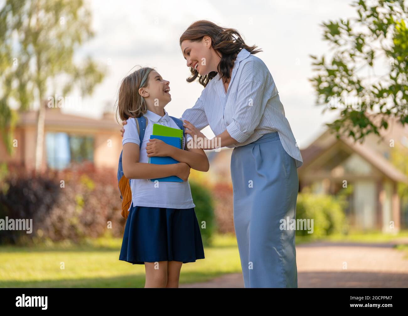 Parent and pupil of primary school going hand in hand. Woman and girl ...