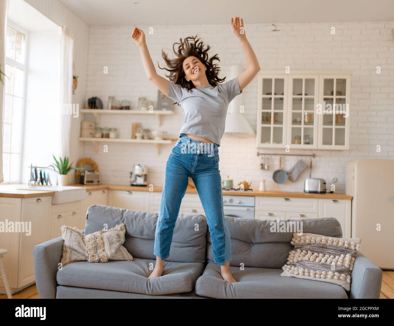 Young woman jumping on sofa hi-res stock photography and images - Alamy
