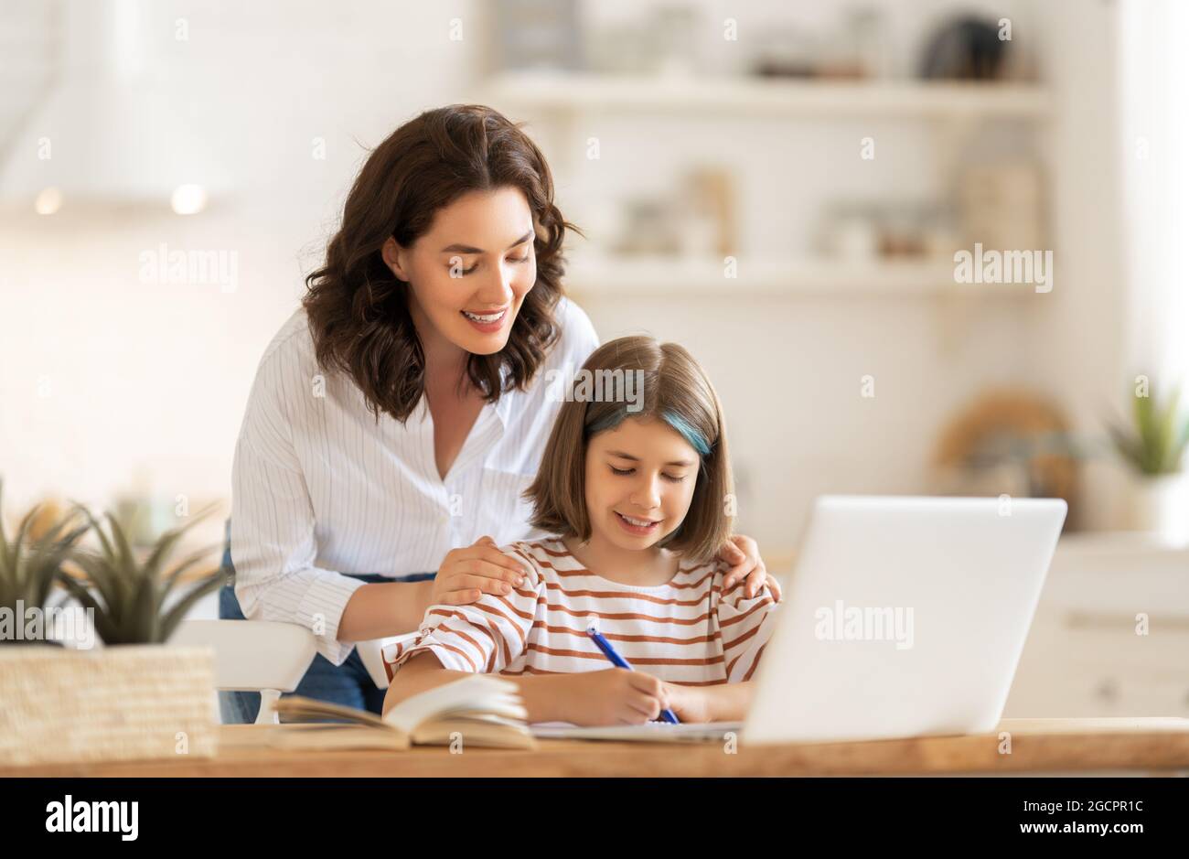 Back to school. Happy child and adult are sitting at desk. Girl doing ...