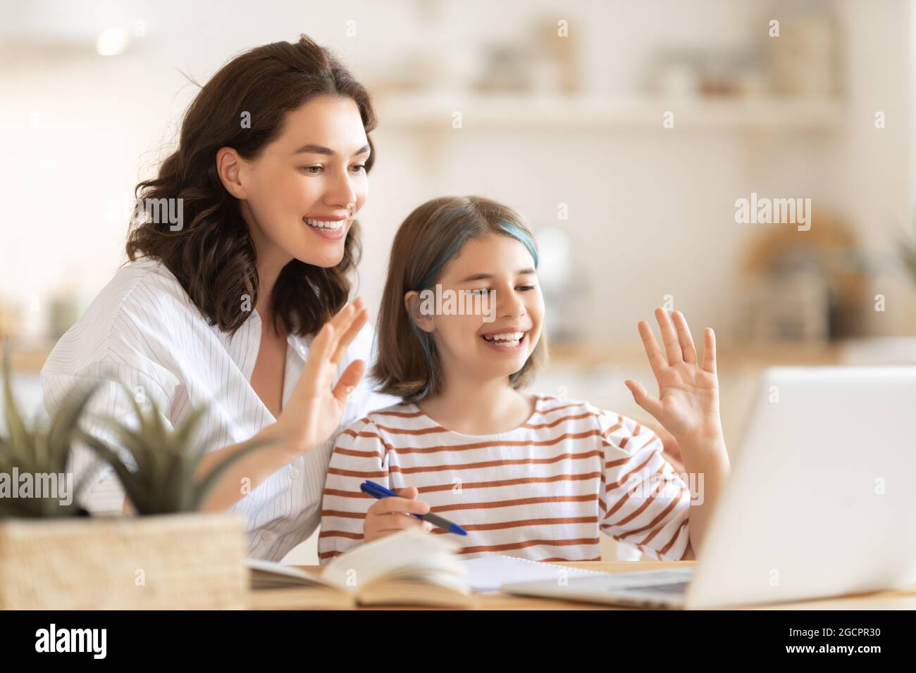 Back to school. Happy child and adult are sitting at desk. Girl doing ...