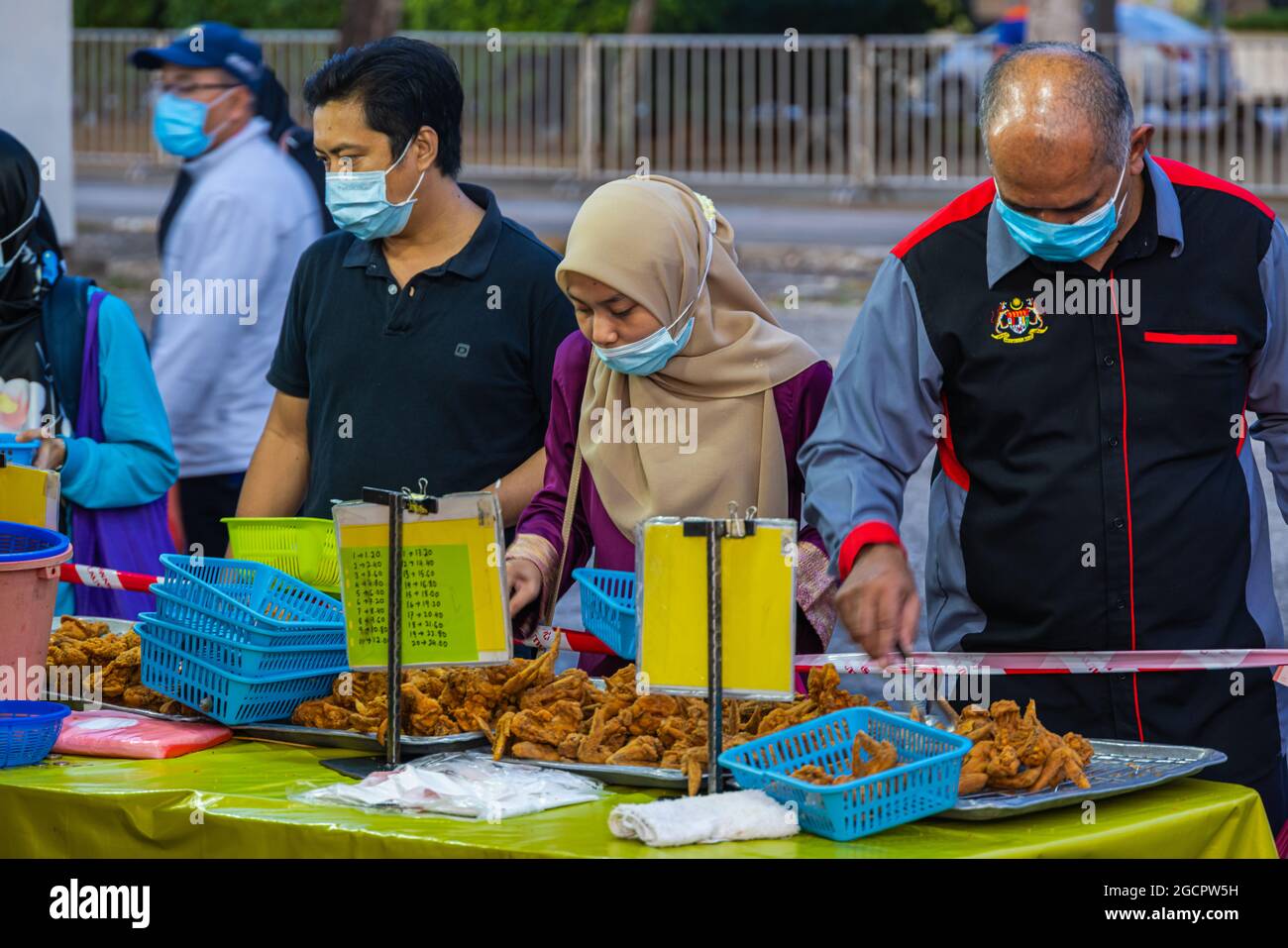 Muslim Malaysian woman at a fried chicken shop in the street market ...