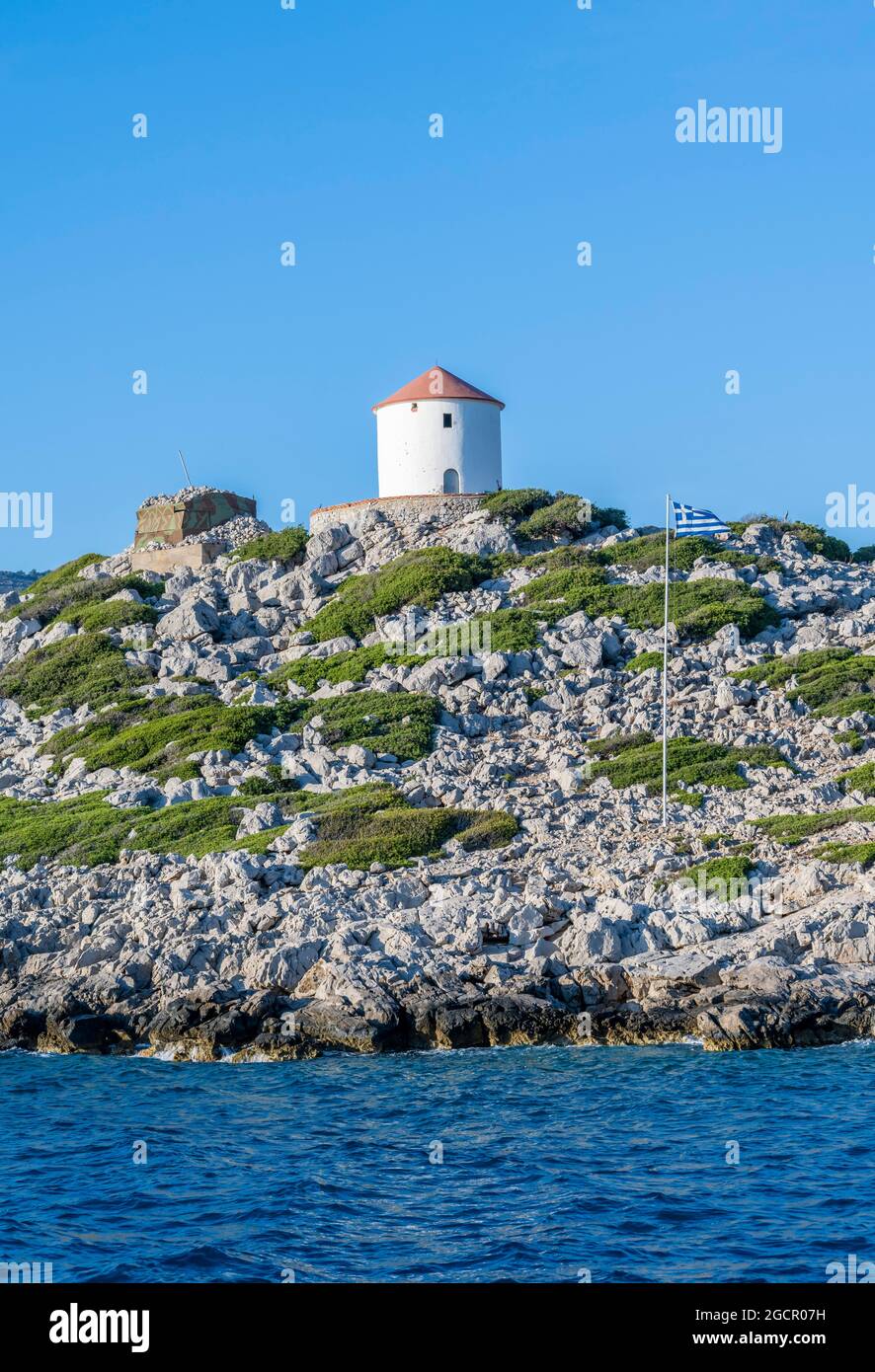 Old windmill on a rock with Greek flag, Bay of Panormitis, Simi ...