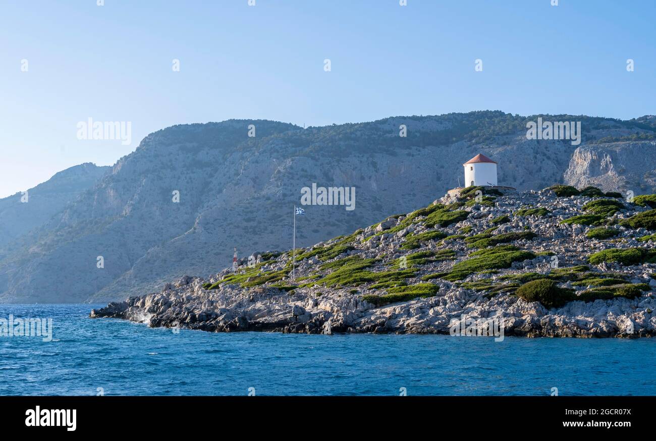 Old windmill on a rock with Greek flag, Bay of Panormitis, Simi ...