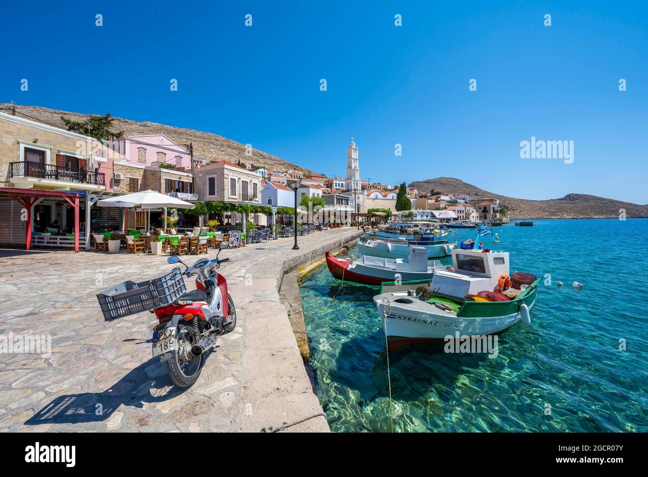 Fishing boats in the harbour of Halki with turquoise water, promenade ...