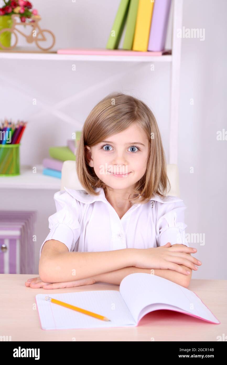 Little girl sitting at desk in room Stock Photo - Alamy