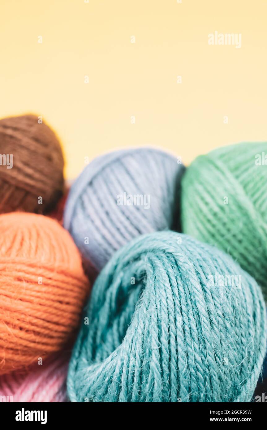 Basket full of colorful yarn rolls isolated on a yellow background with ...