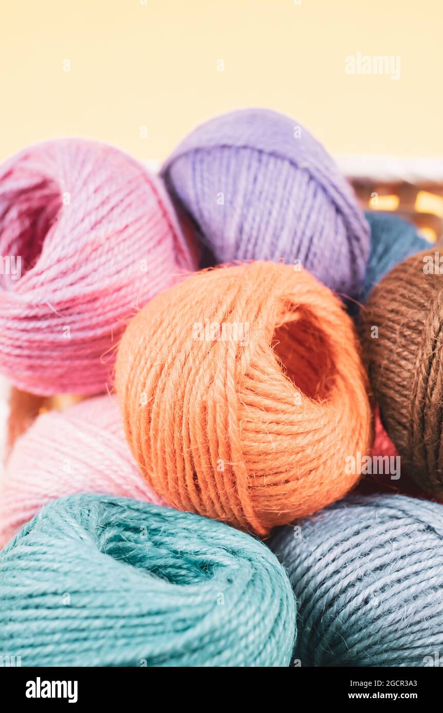 Basket full of colorful yarn rolls isolated on a yellow background with ...