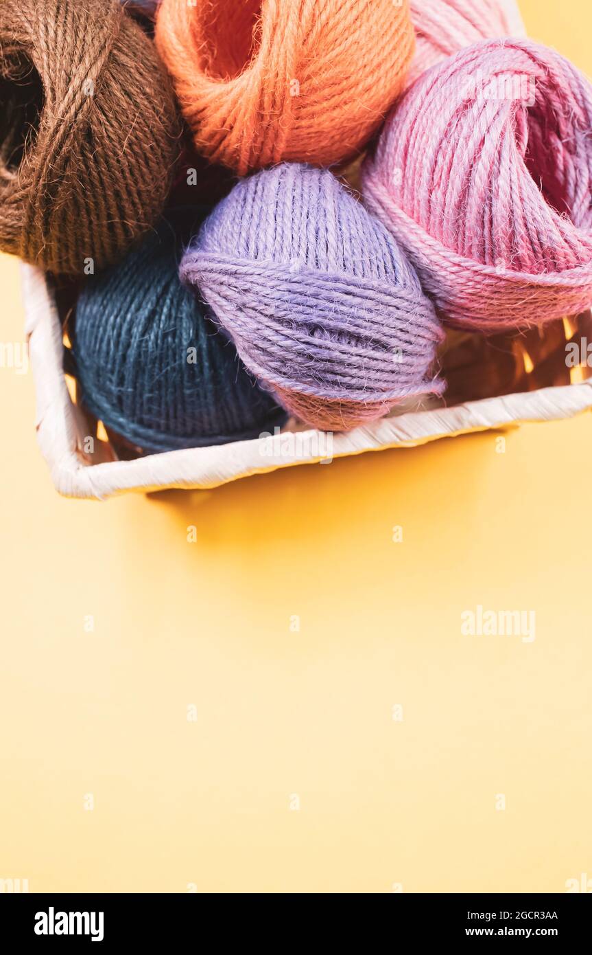 Basket full of colorful yarn rolls isolated on a yellow background with ...