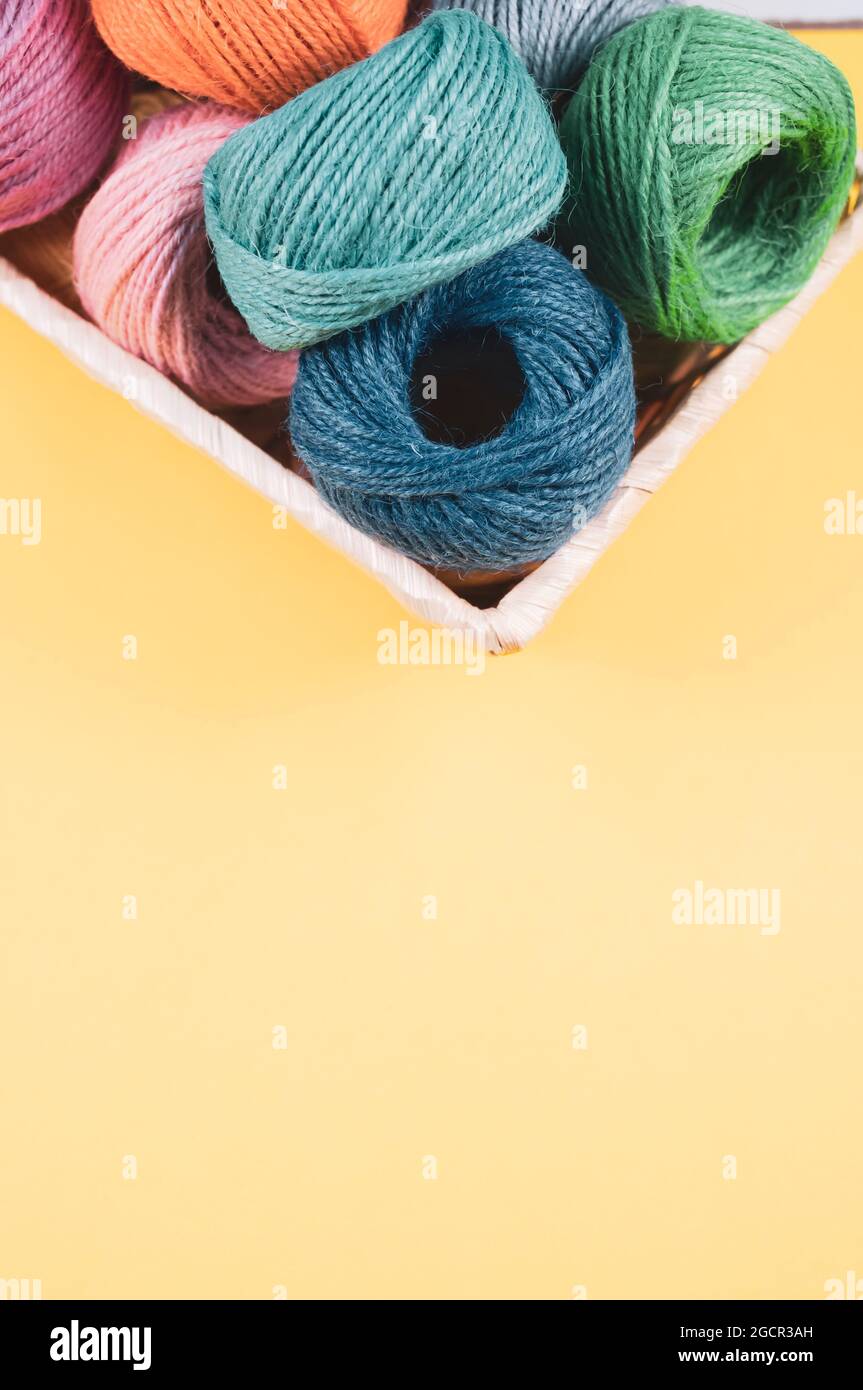 Basket full of colorful yarn rolls isolated on a yellow background with ...