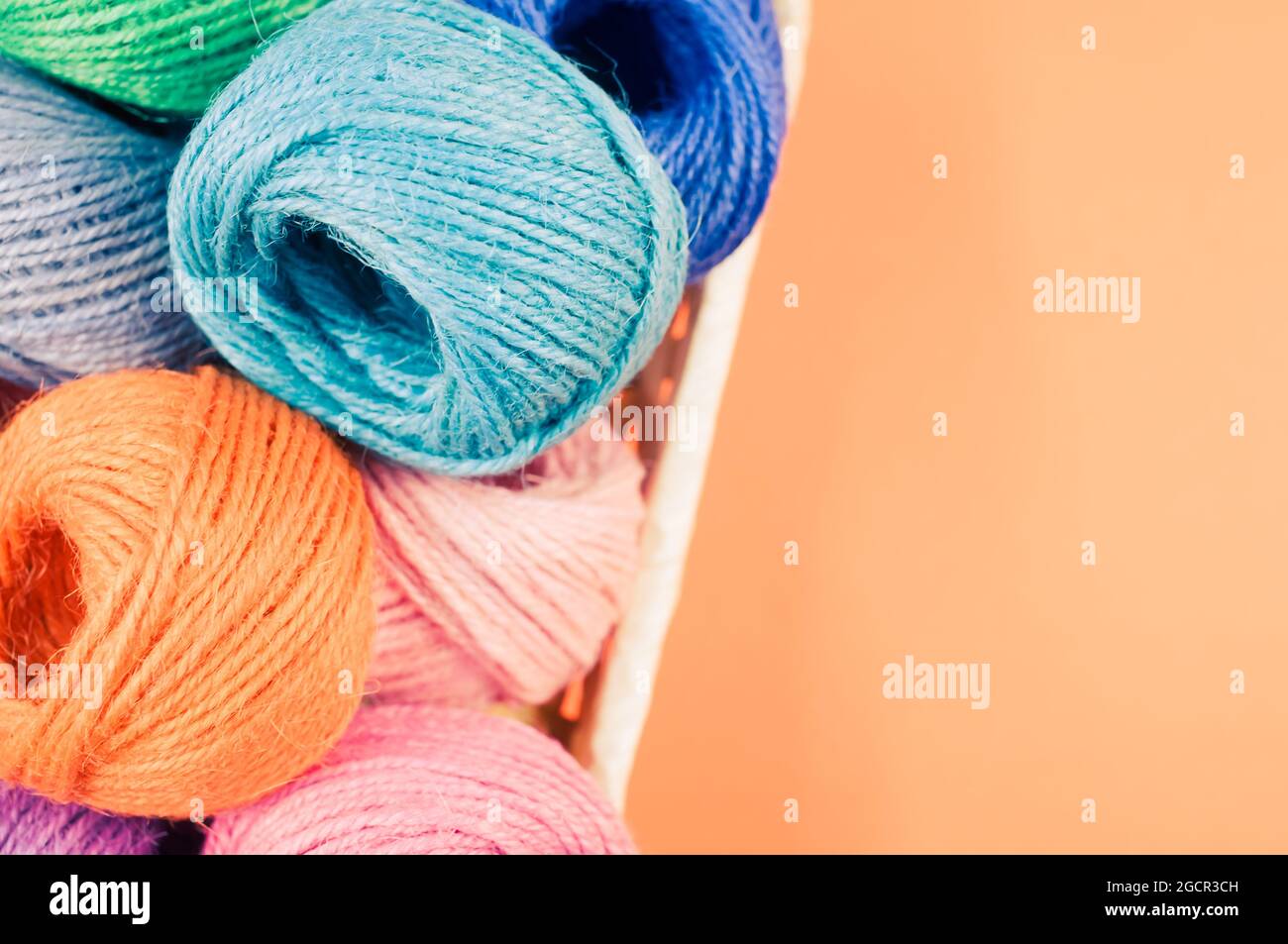 Basket full of colorful yarn rolls isolated on an orange background ...