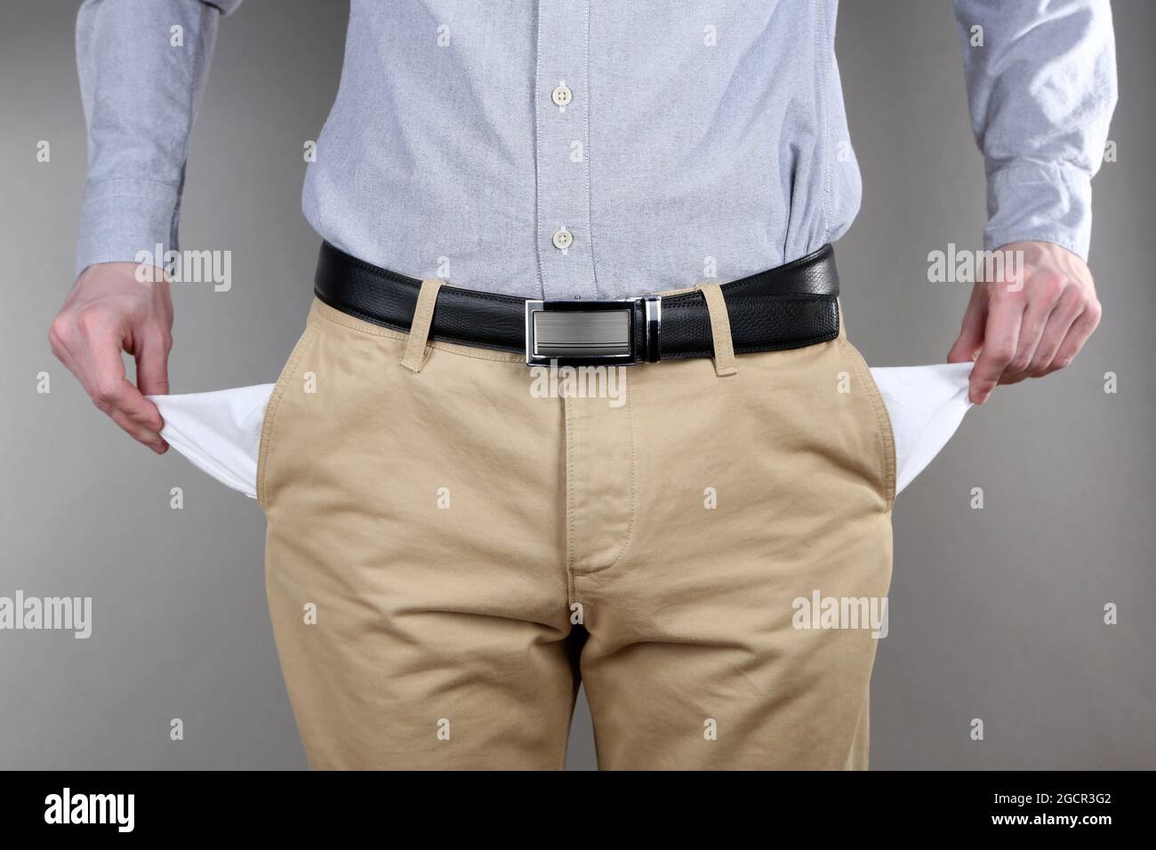 Man showing his empty pockets on grey background Stock Photo - Alamy