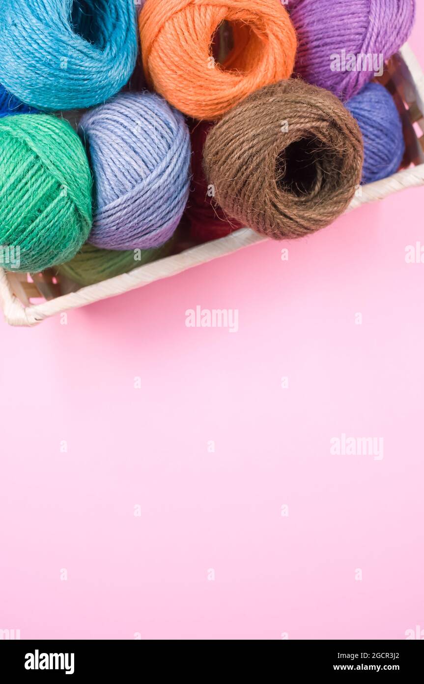 Basket full of colorful yarn rolls isolated on a pink background with ...