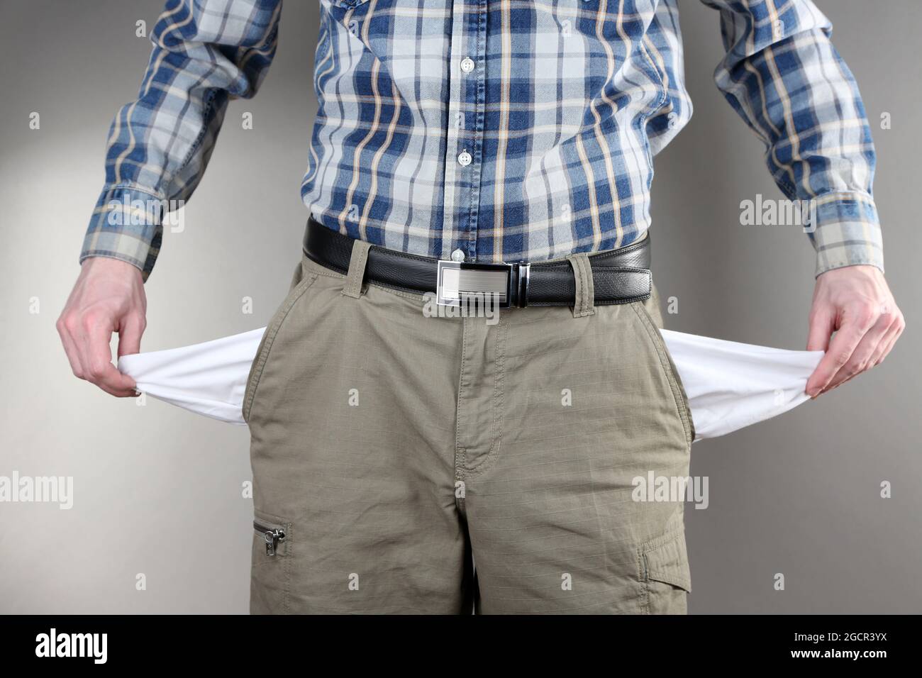 Man showing his empty pockets on grey background Stock Photo - Alamy