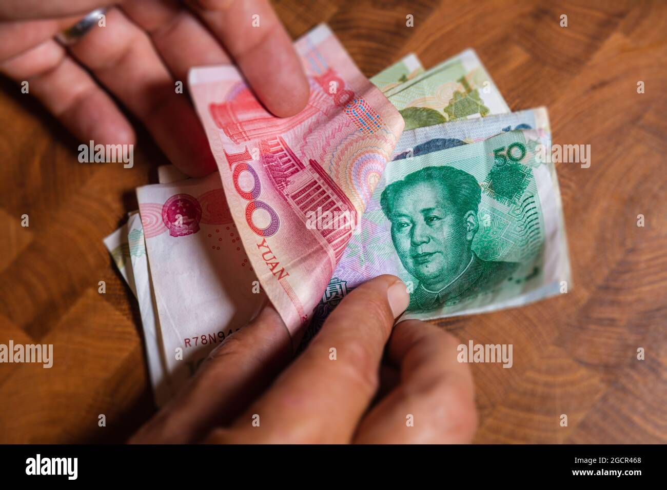 Male hand shows Renminbi or Chinese yuan or abbreviated RMB banknote ...