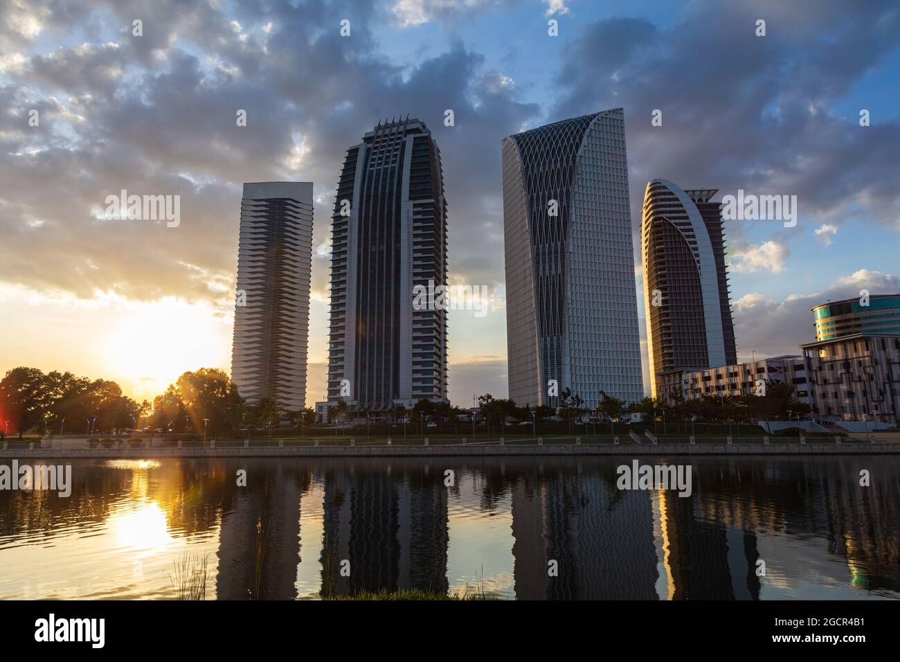 Skyscraper in sunset, in front a lake with reflections of the buildings ...
