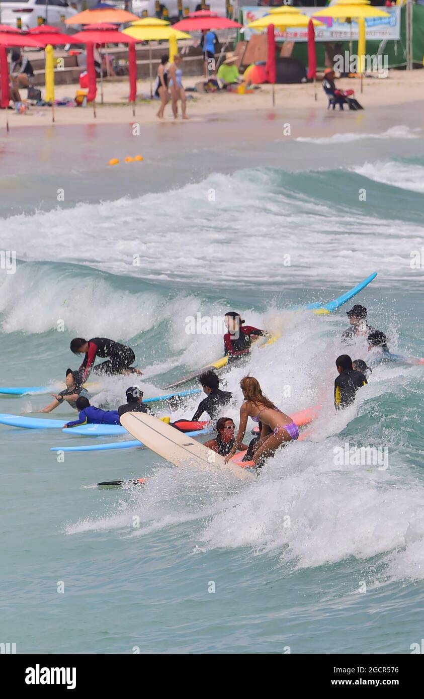 10th Aug, 2021. Surfing off Jeju Island Surfers ride waves off a beach ...