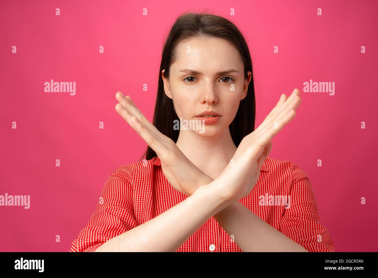 Young attractive woman showing a rejection gesture on a pink background ...