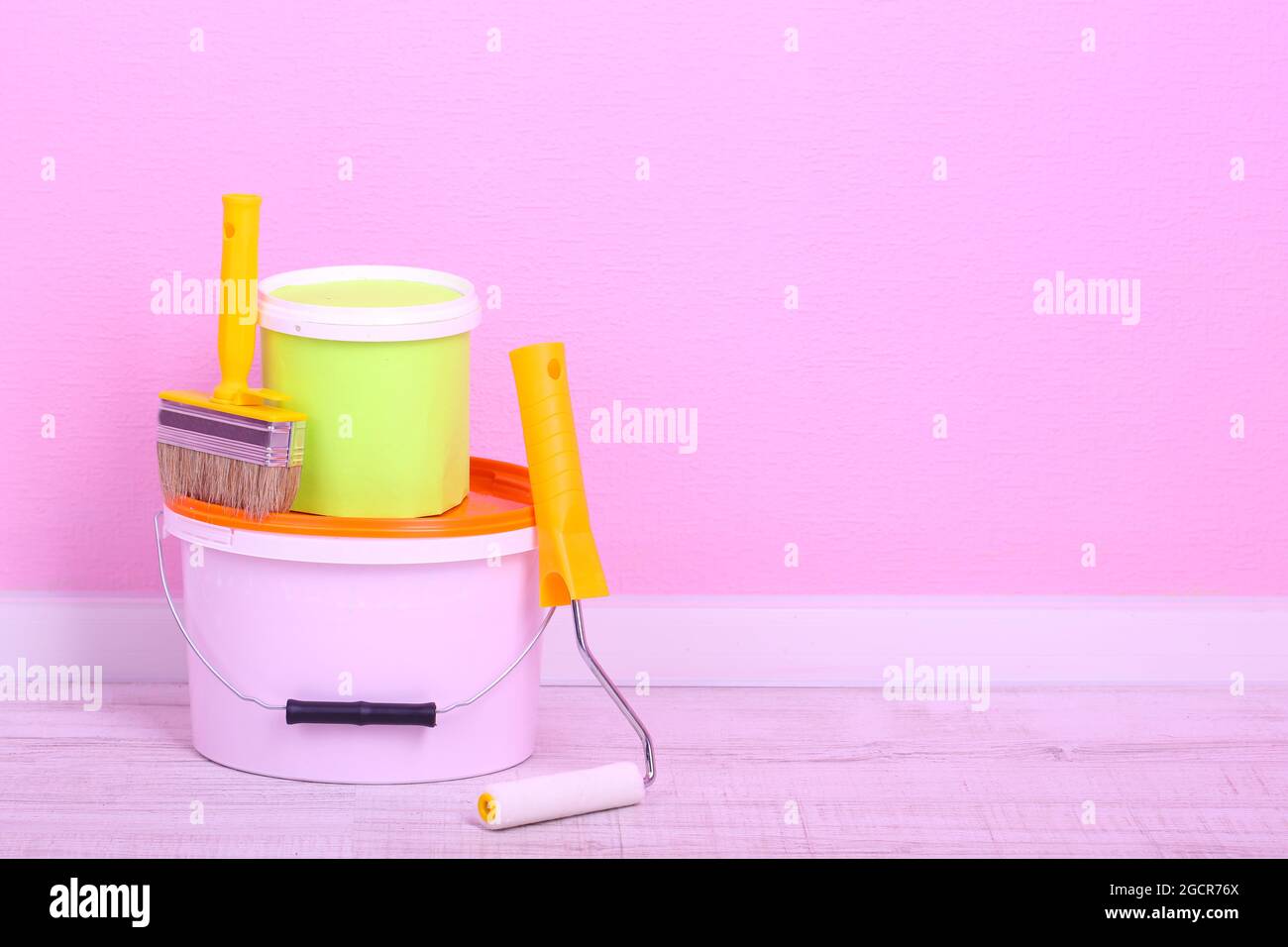 Paints, roll and paintbrush on floor in room on wall background Stock ...