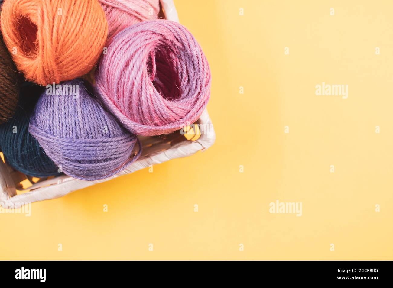 Basket full of colorful yarn rolls isolated on a yellow background with ...