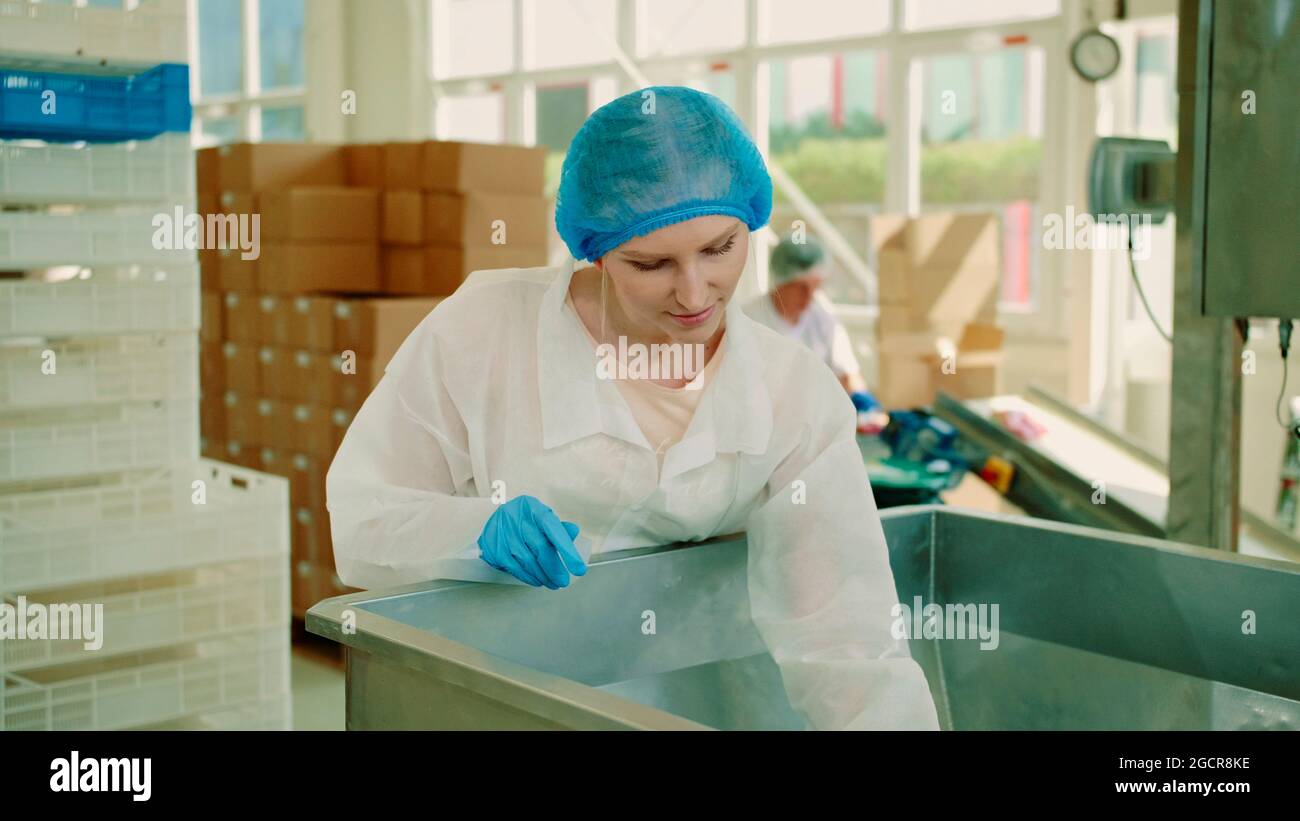 Candy factory. Factory worker checking packing machine. Young woman in ...