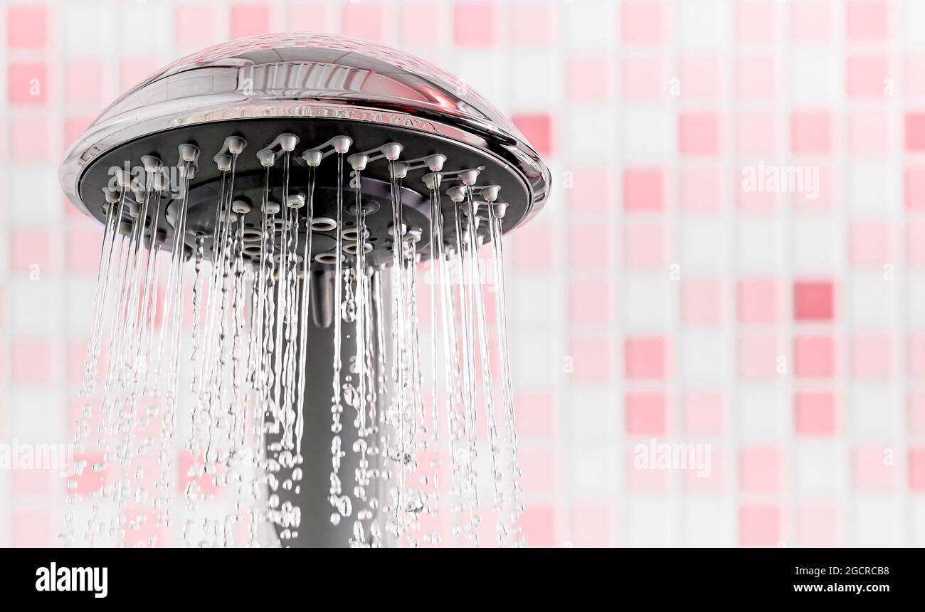 Shower head with flowing water stream in pink bathroom Stock Photo - Alamy