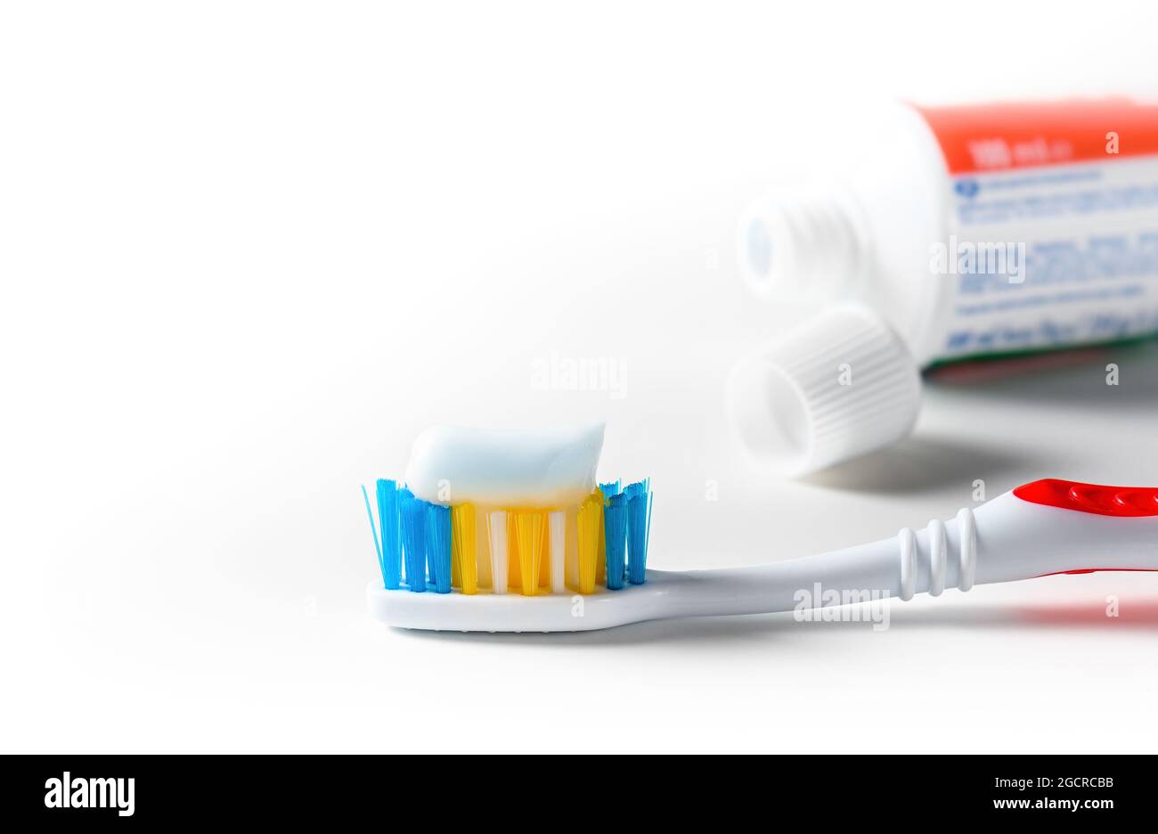 Toothbrush with toothpaste and tube of toothpaste over white background ...