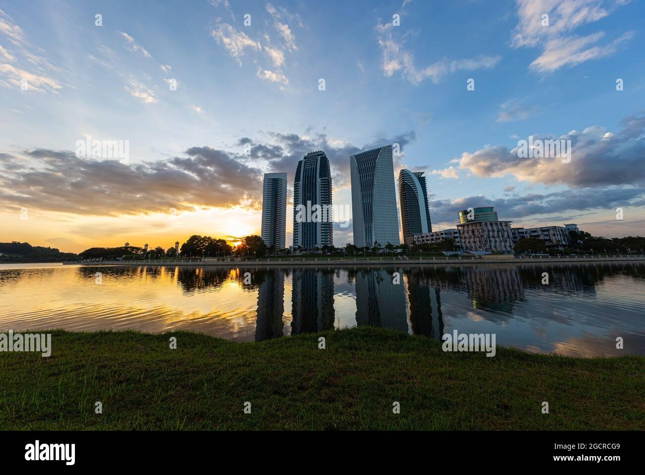 Skyscraper in sunset, in front a lake with reflections of the buildings ...