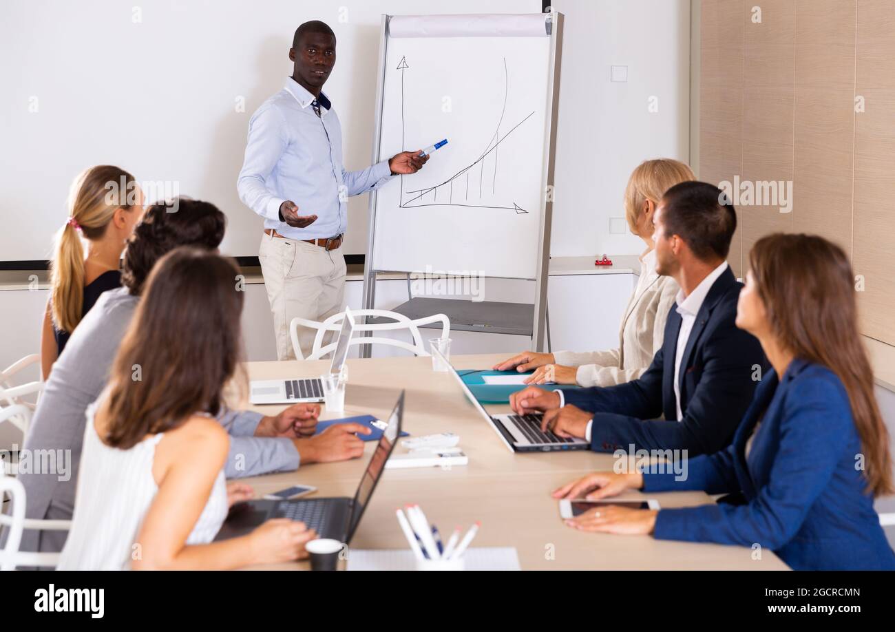 African man presenting business project to coworkers Stock Photo - Alamy
