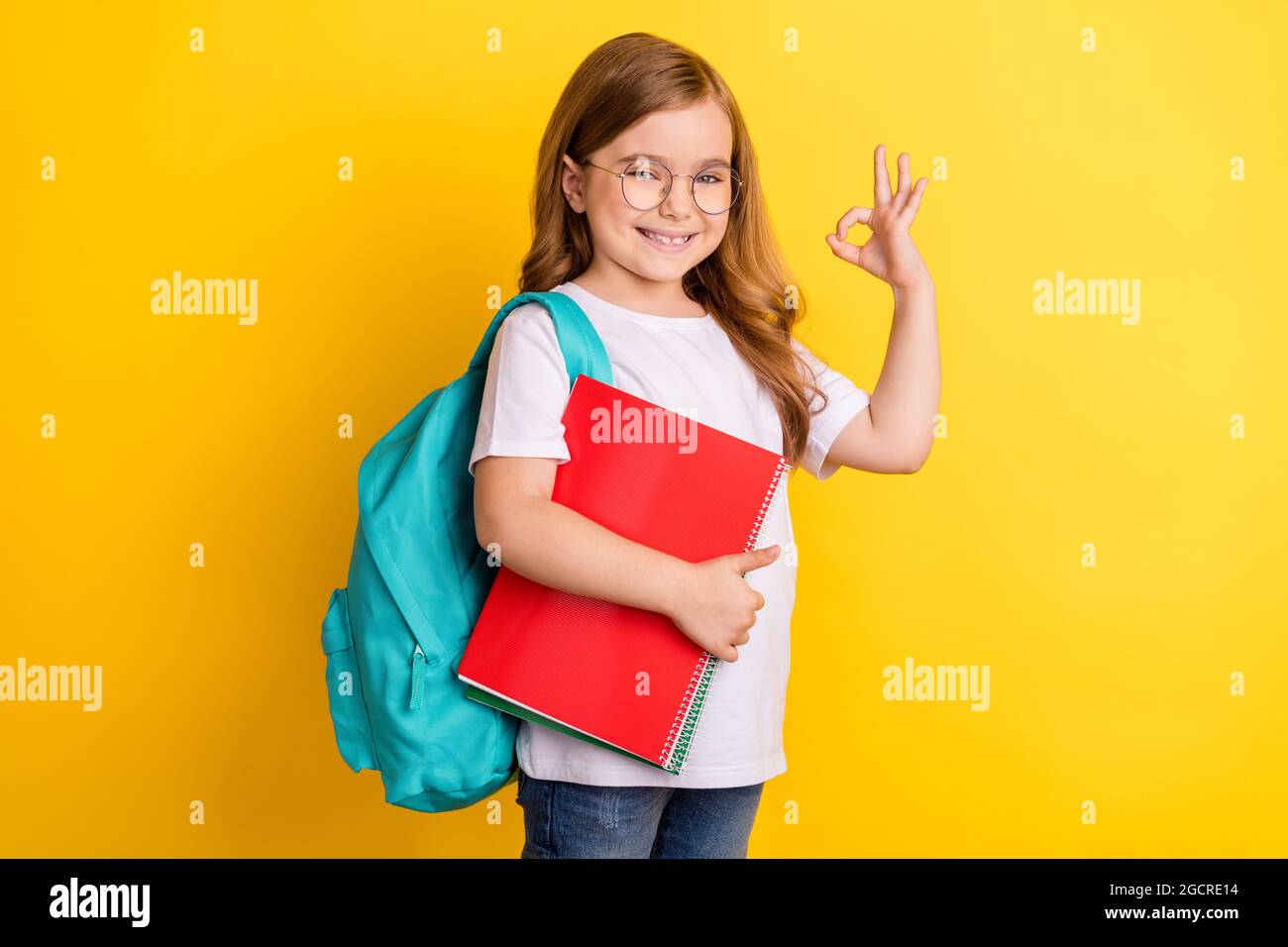 Photo of little funny blond girl show okey hold book wear spectacles ...