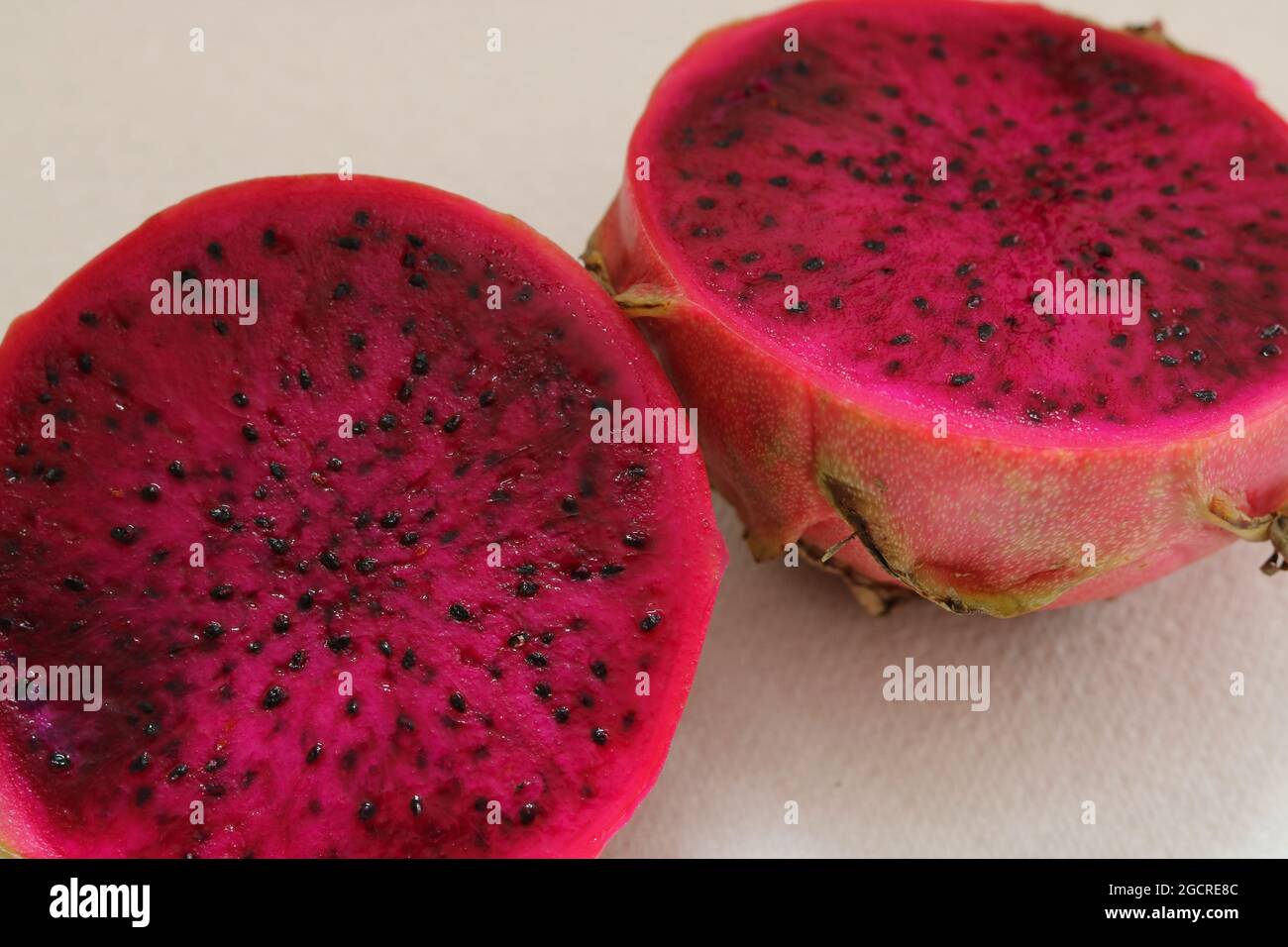 Pithaya cut in half showing dark pink interior and black seeds Stock ...