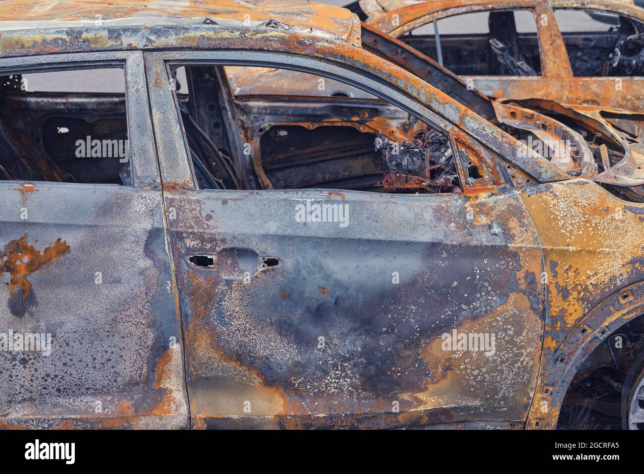 Burnt-out rusty cars on a city street, vandalism. Setting fire to cars ...