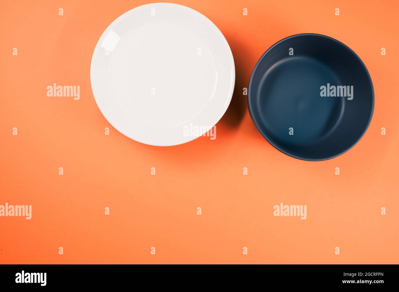 Top view of an empty ceramic black and white plates on a orange ...