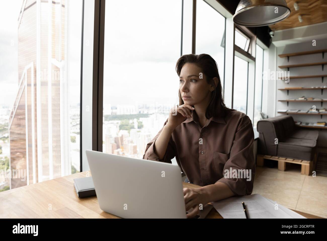 Serious female business leader, entrepreneur looking out of window ...