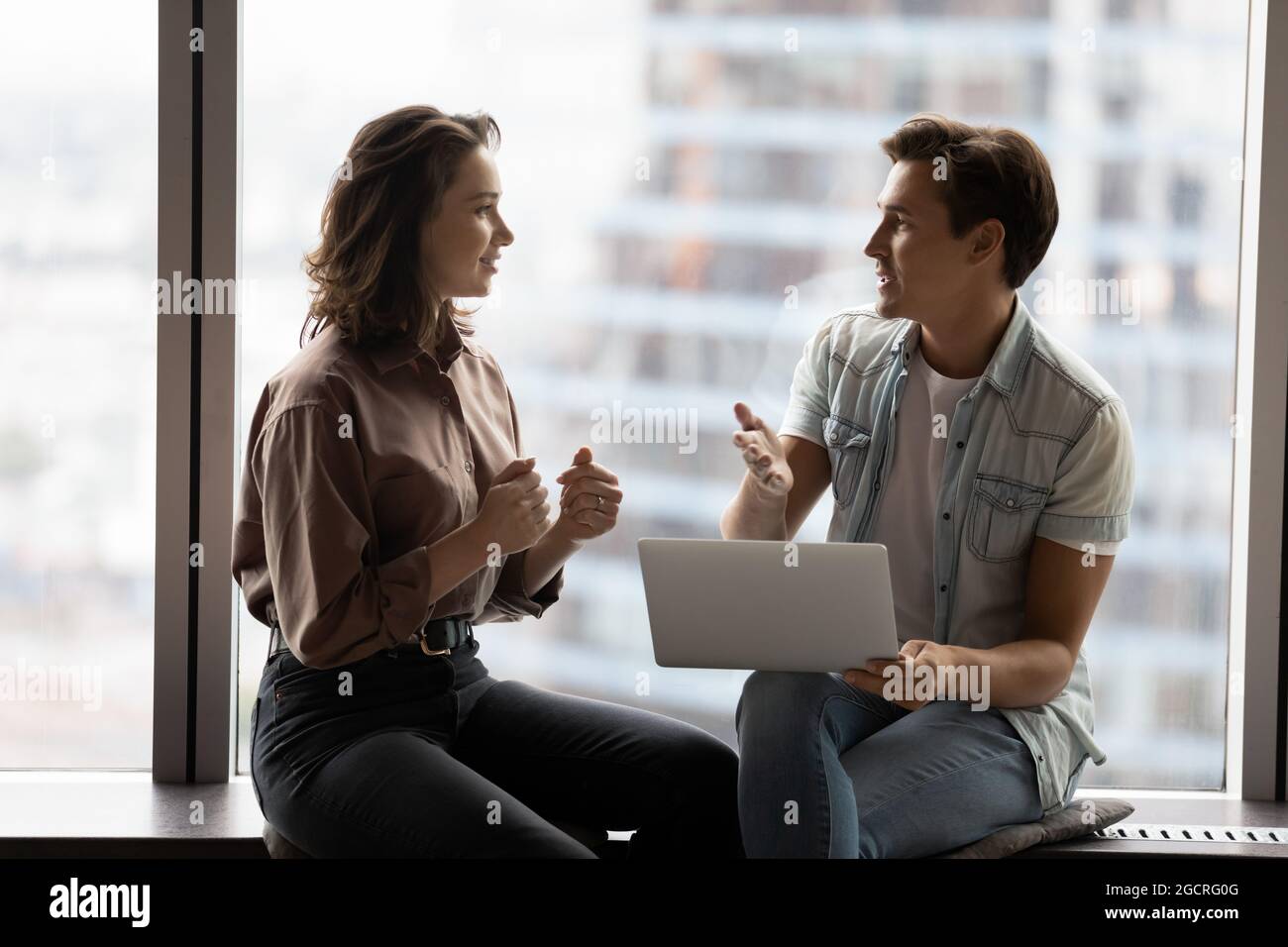 Team members, coworkers sitting at panoramic window, discussing work ...