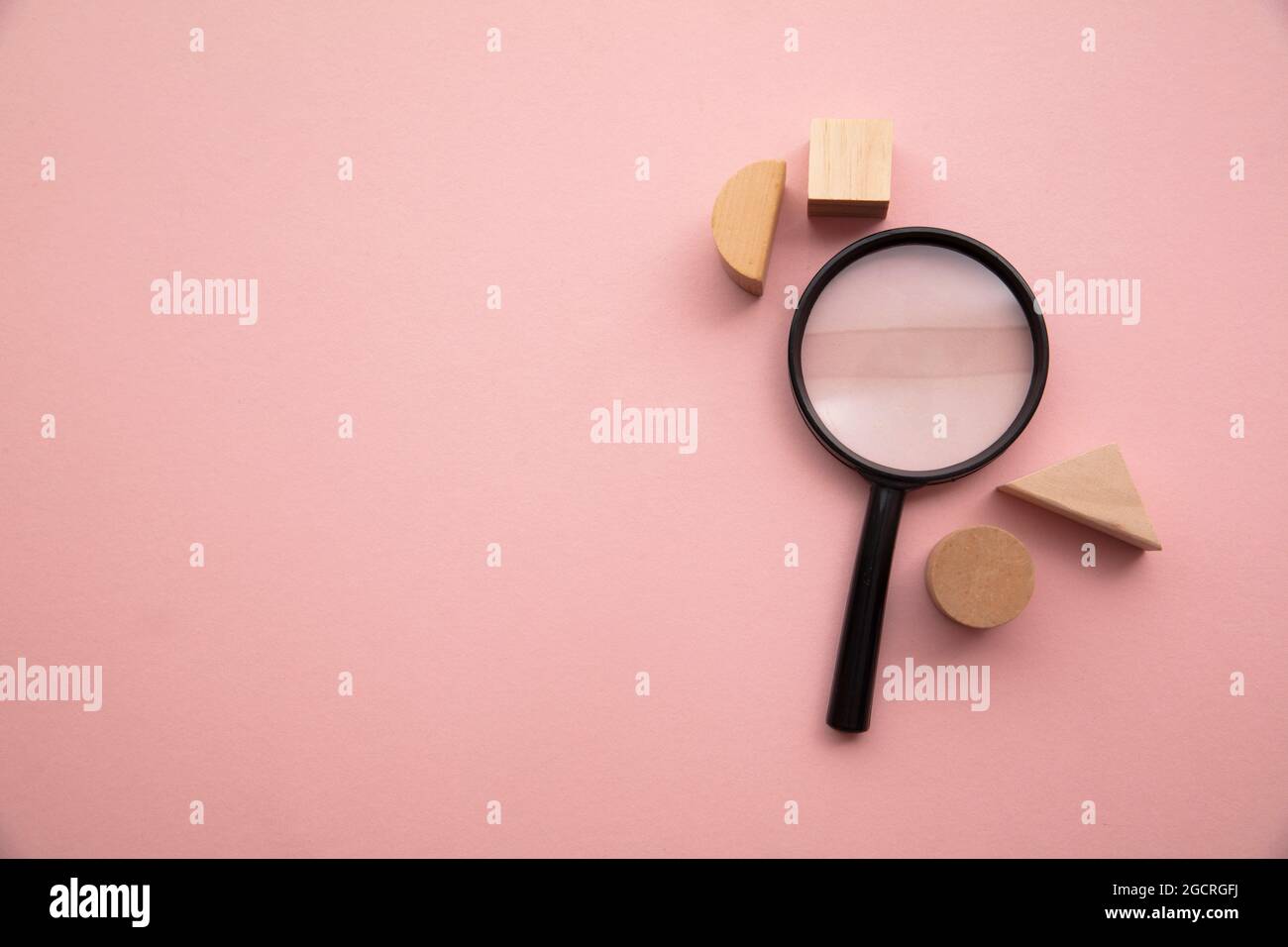 Magnifying glass with a selection of different shaped wooden blocks ...