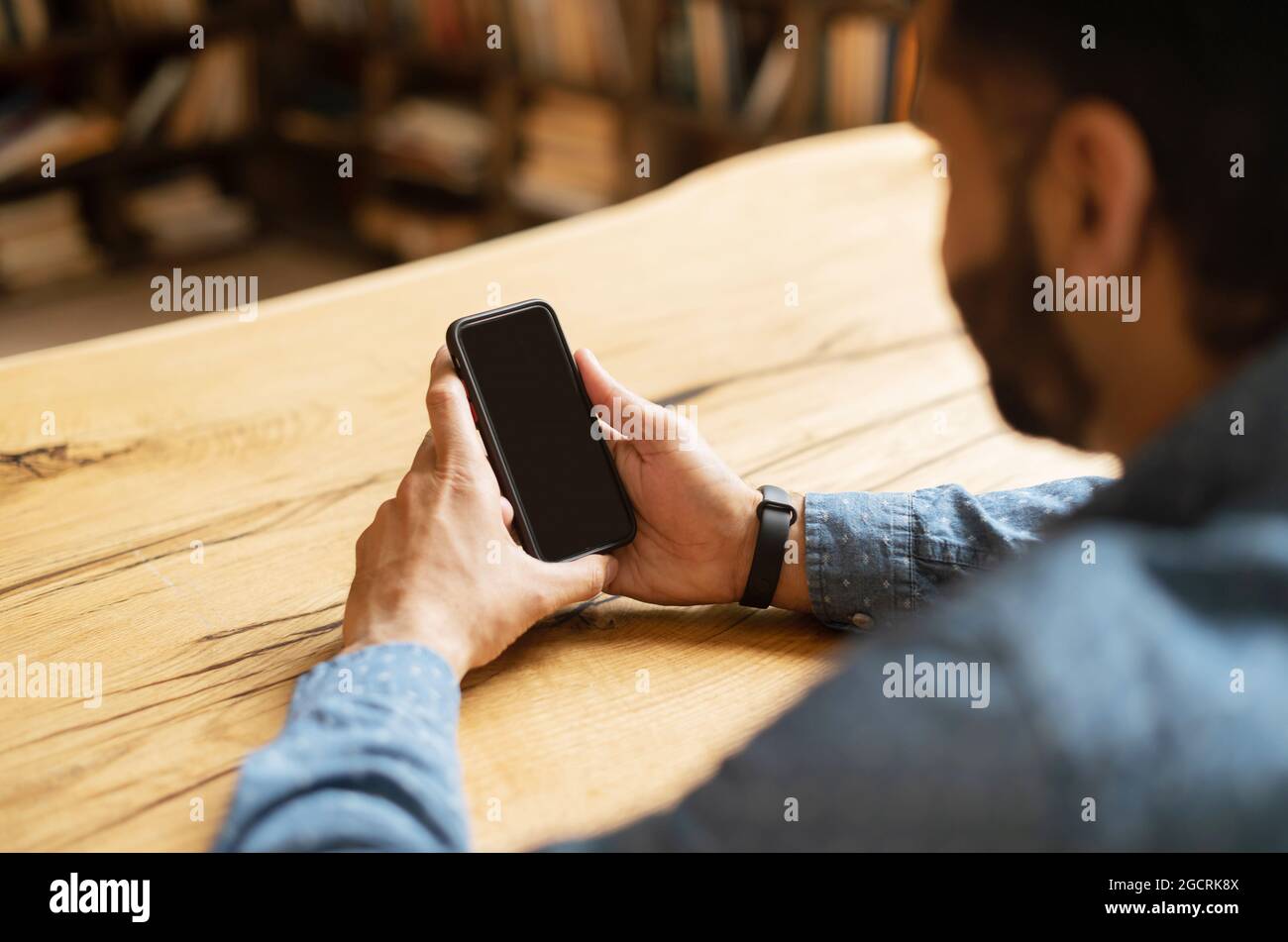 Indian bearded man holding a black mobile phone with blank screen, using new mobile app, male ...