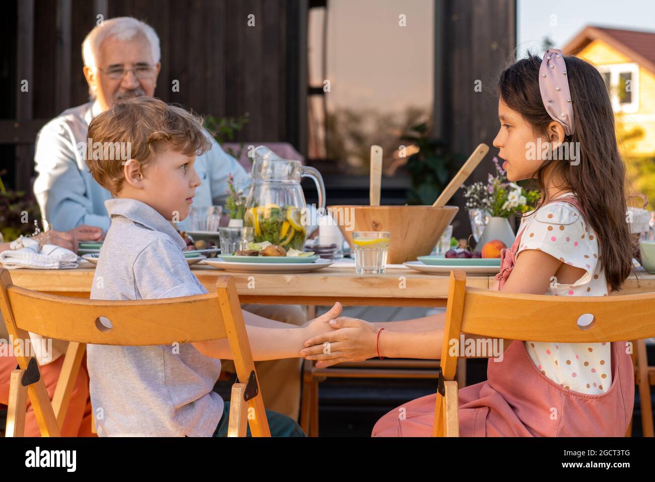 Two kids playing by served table during family dinner against their ...