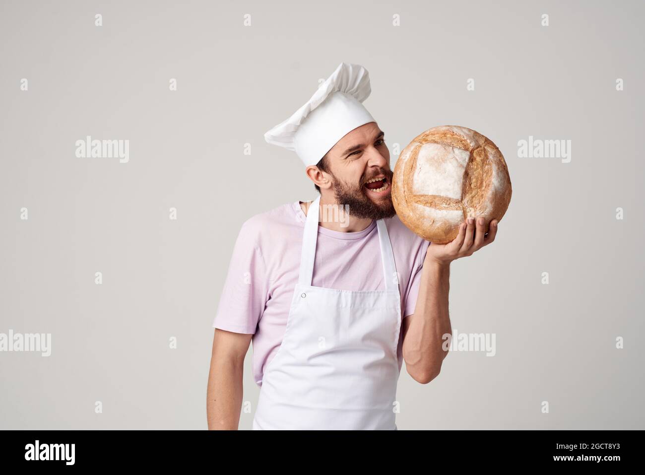 bearded man in a white apron with bread in the hands of a baker Stock ...