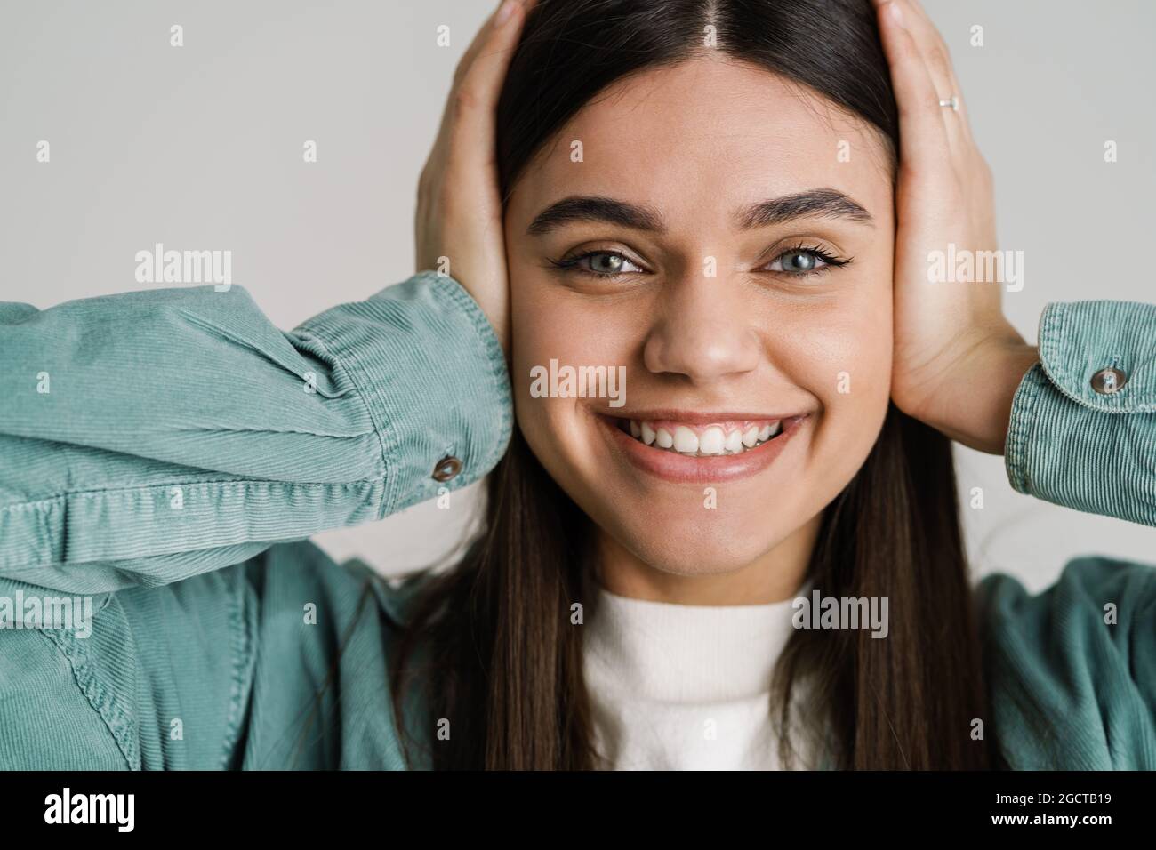 Young smiling woman looking at camera while holding her head isolated ...