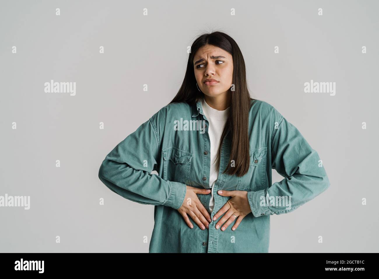 Young unhappy woman with stomachache rubbing her belly isolated over ...