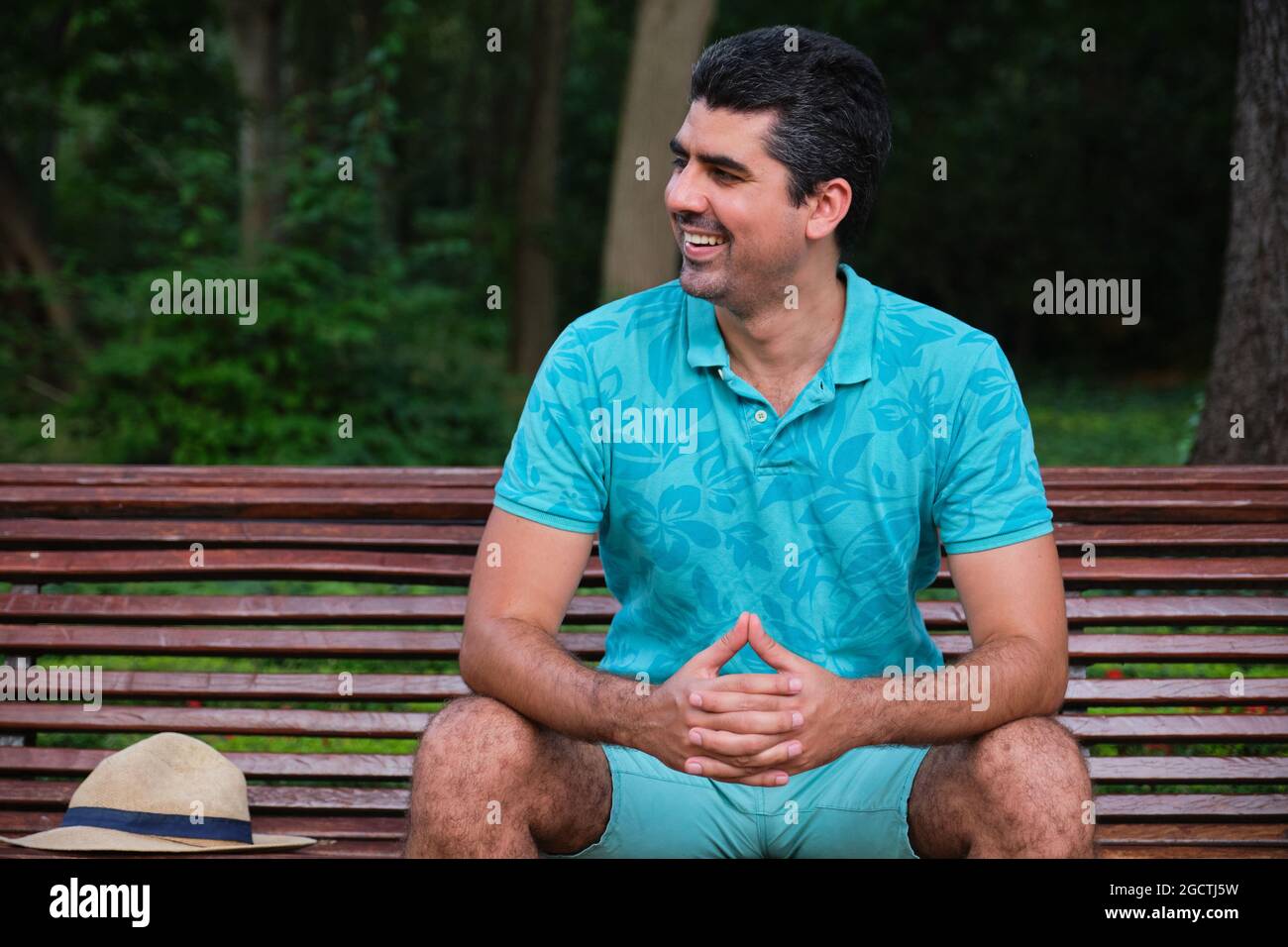 Man smiling sitting on a bench looking at a side Stock Photo - Alamy