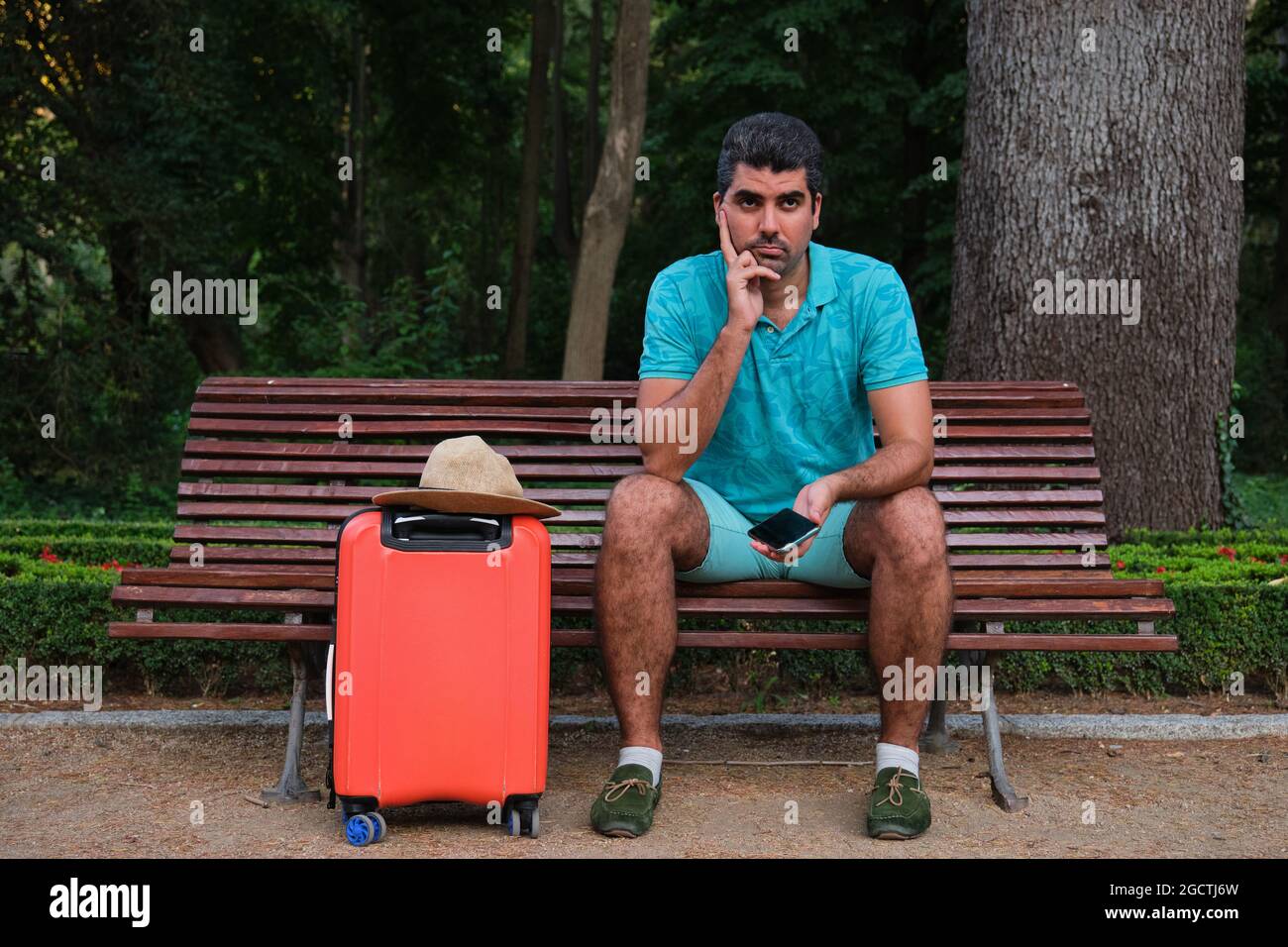 Tourist man sitting on a bench bored, waiting for someone Stock Photo ...