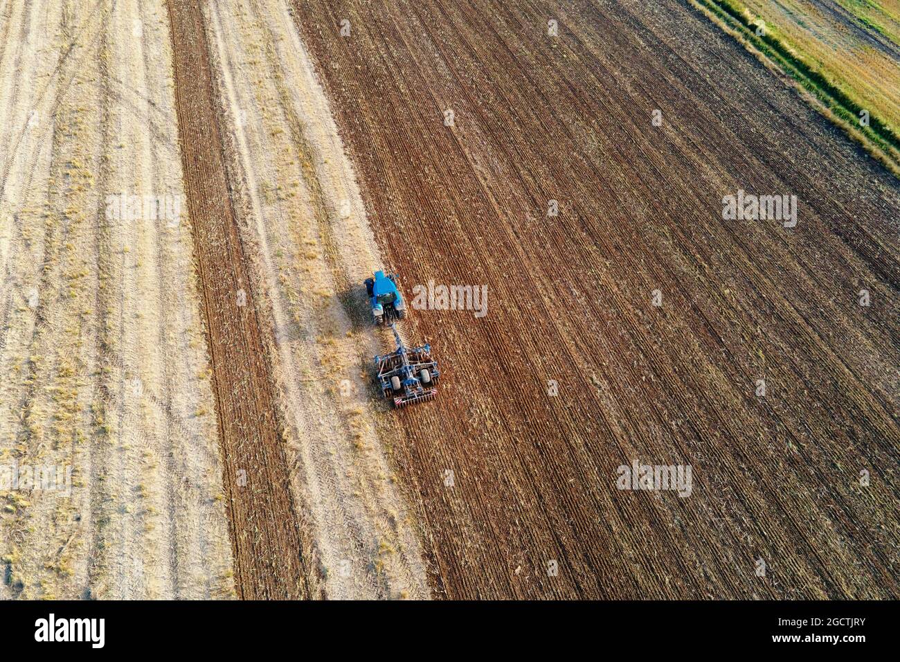 Tractor plows ground on cultivated farm field. Aerial view of tractor ...
