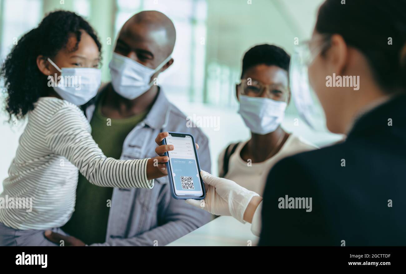Airport staff checking medical pass on mobile phone of passenger at ...