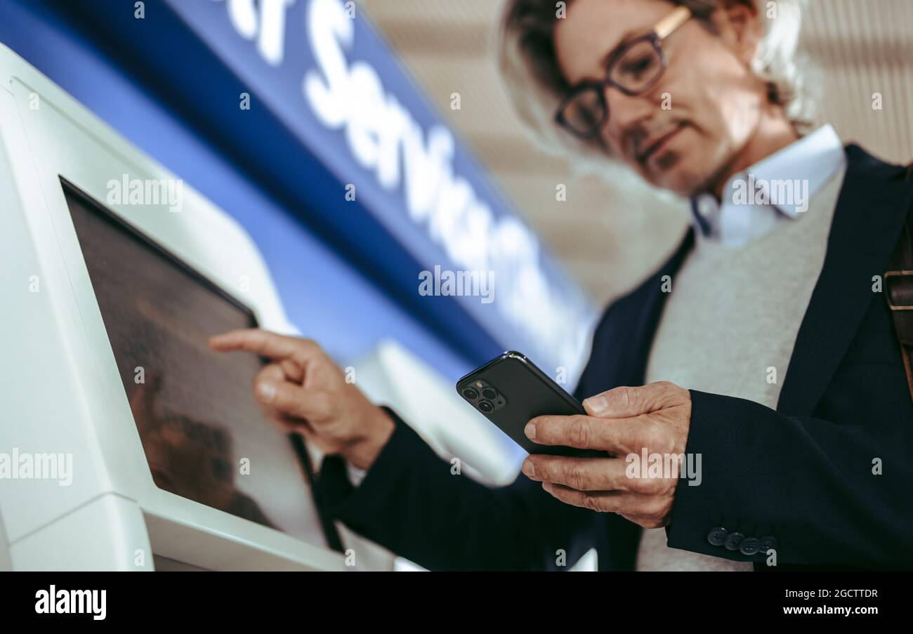 Businessman standing in an airport terminal and checking his smart ...
