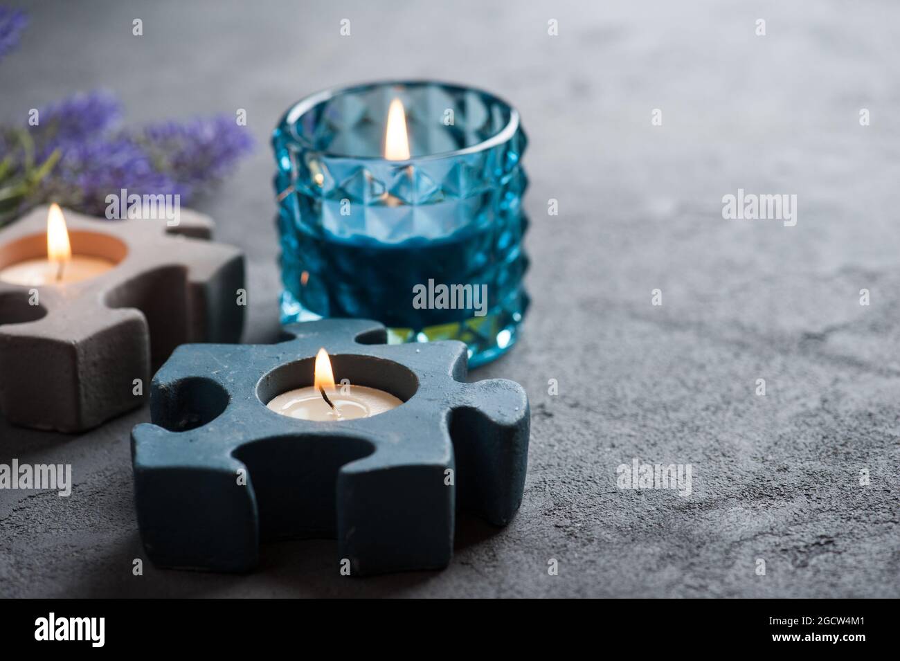Candlesticks with burning candles on stone background. Blue tint ...