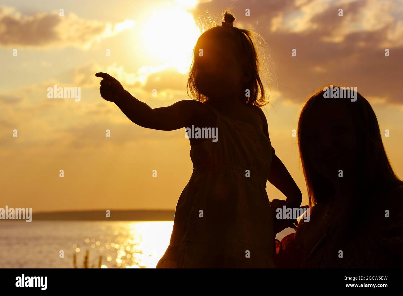 Silhouette of a young mother and infant baby girl pointing her finger ...